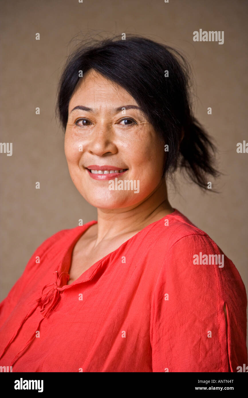 Middle Aged Asian Oriental Chinese Woman In Orange Dress Smiling Stock