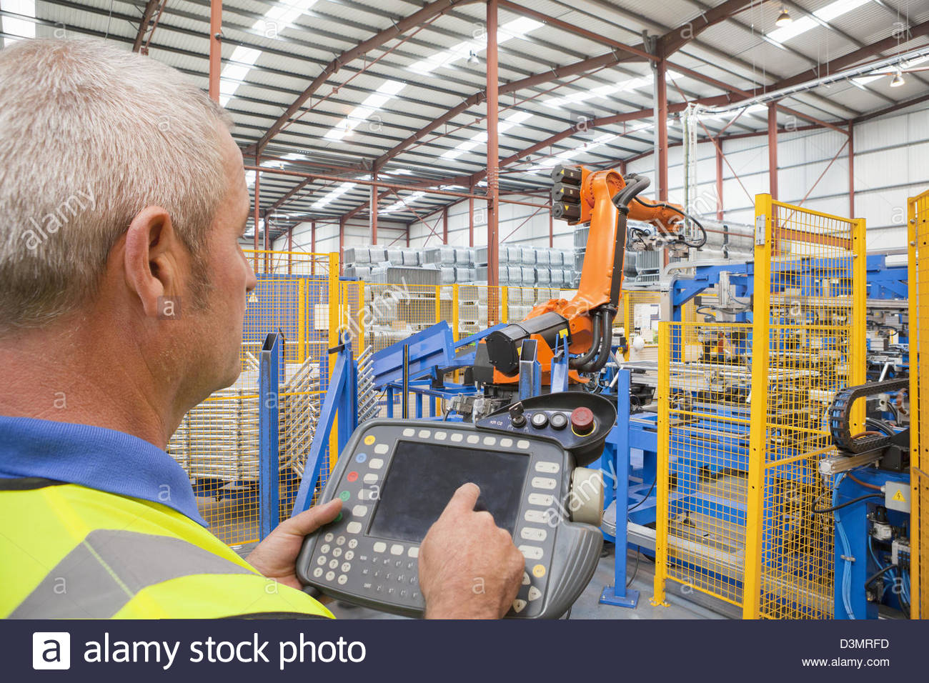 Worker operating robotic machinery in factory Stock Photo, Royalty Free ... Worker operating robotic machinery in factory Stock Photo, Royalty Free ...