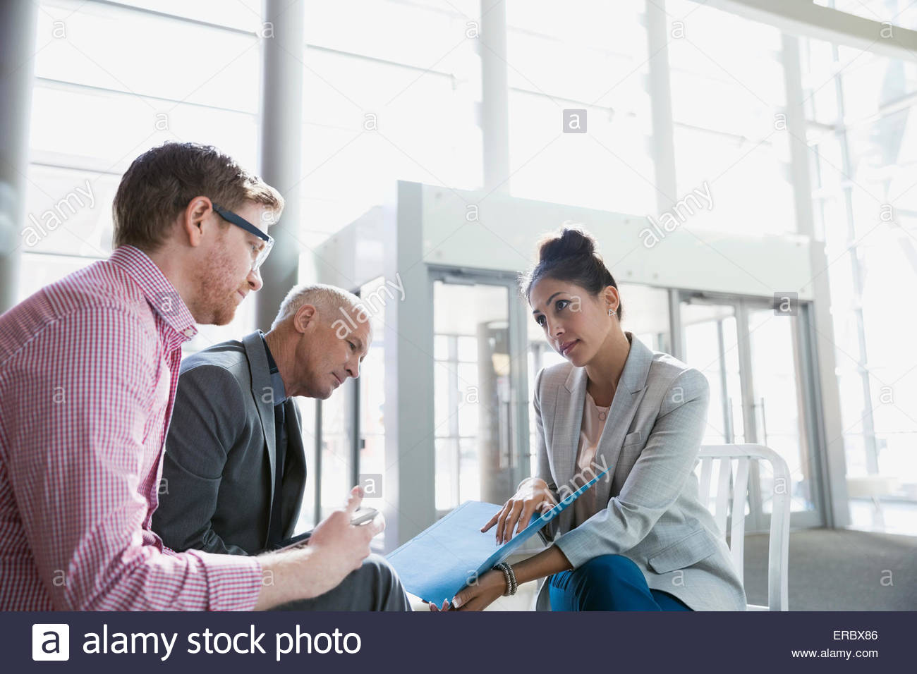 Business people reviewing paperwork in lobby Stock Photo, Royalty Free ... Business people reviewing paperwork in lobby Stock Photo, Royalty Free ...