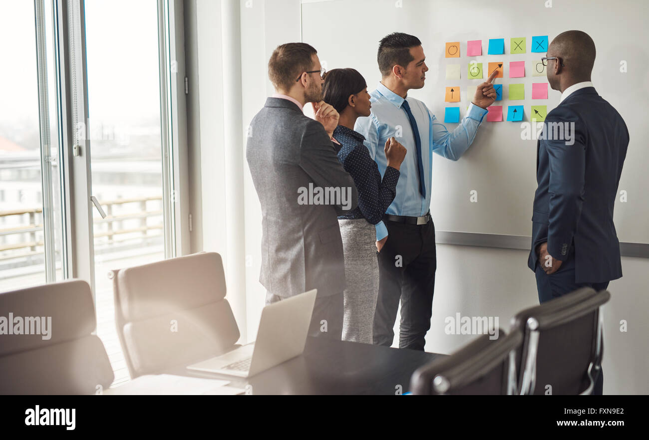 Diverse group of four business people gathered around white board Stock ... Diverse group of four business people gathered around white board Stock ...