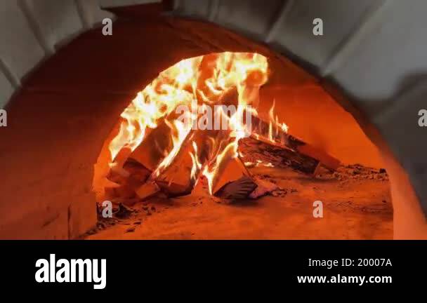 Flames illuminate a traditional oven as logs crackle and burn. The warm ...