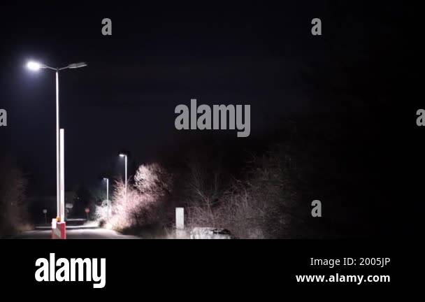 A quiet, dark street at night with three street lights illuminating the ...