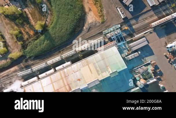 Trains are visible on tracks next to industrial facilities surrounded ...