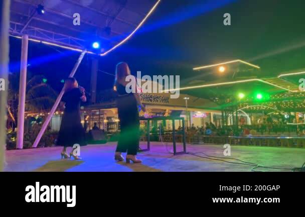 Two female singers performing on a brightly lit outdoor stage at a ...