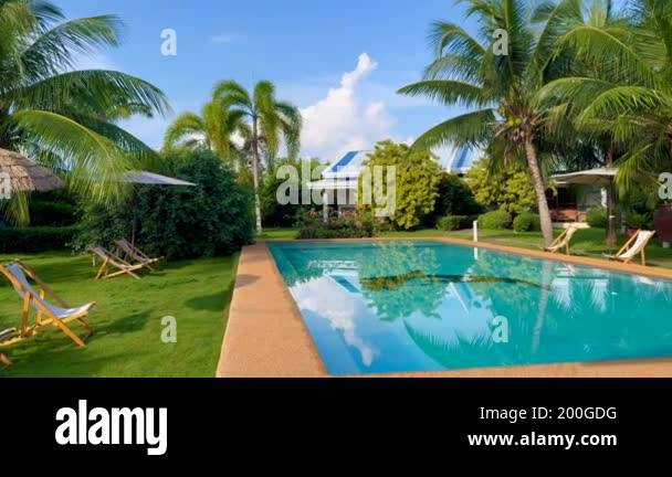 A serene tropical villa surrounded by lush greenery, palm trees, and a sparkling blue swimming ...