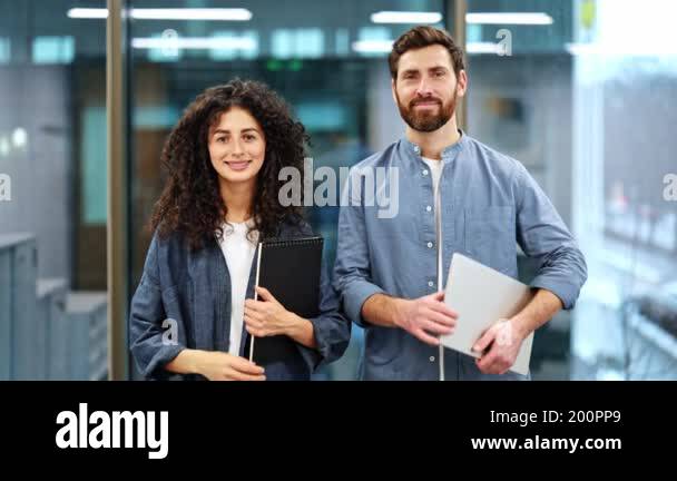 Two happy business professionals, female and male, coworkers, smile at ...