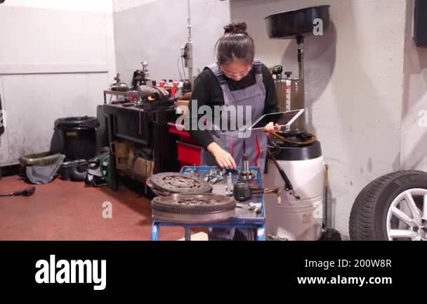 Professional female mechanic examining various car parts, ensuring ...