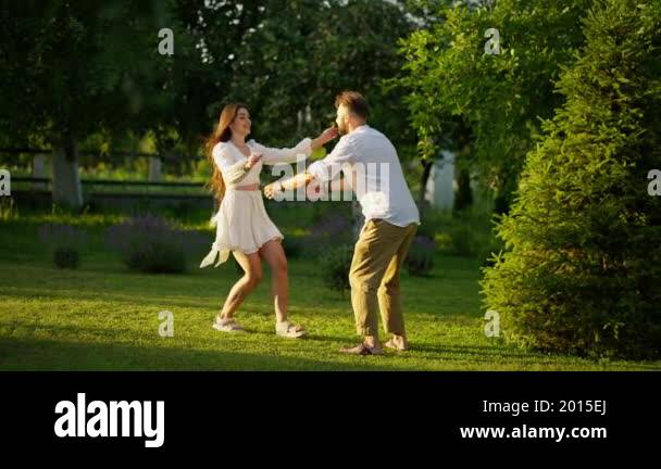 A joyful couple shares a playful embrace in a vibrant garden surrounded ...