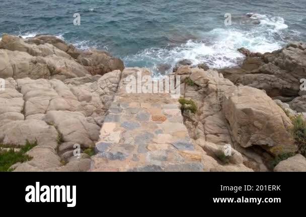 Stone pathway leads to a rocky shoreline, offering a scenic view of the ...