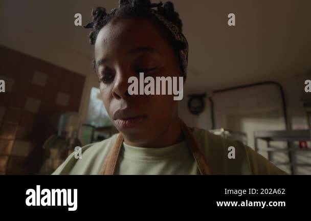 Tilt down shot of African American female baker carefully decorating ...