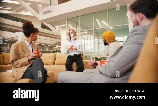 Diverse team men and women enjoys coffee break in office building ...