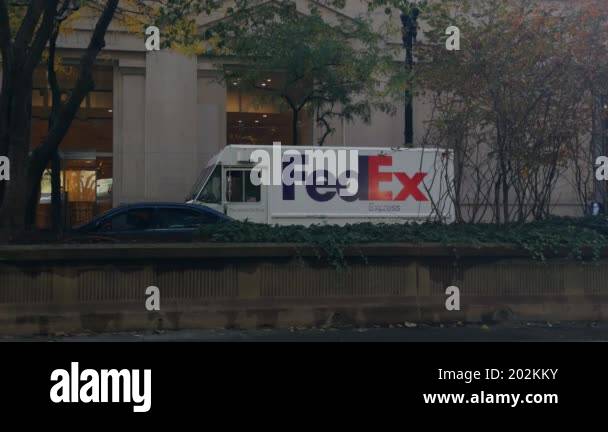 FedEx driver delivers package to local on a van in downtown. Front view ...