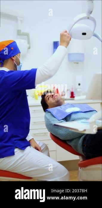 vertical Dentist preparing for a dental procedure, adjusting the dental ...