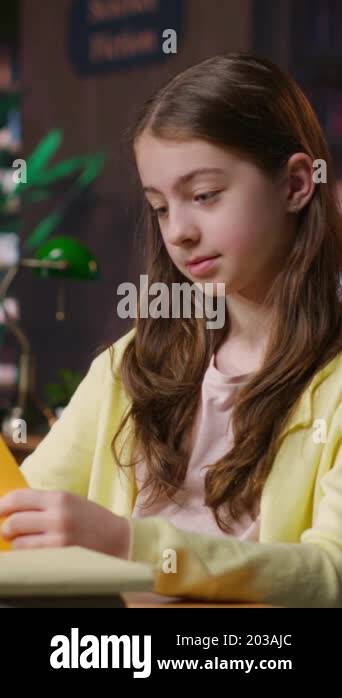 Vertical Video Young teen girl engrossed in reading books at the school ...