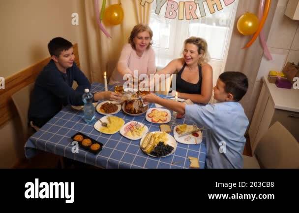 Celebrating a woman's birthday, people sit down at the table, drink and ...