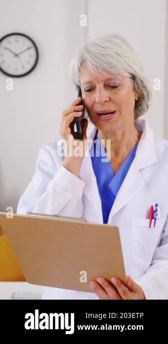 Vertical video. Smiling doctor reading some medical reports while ...