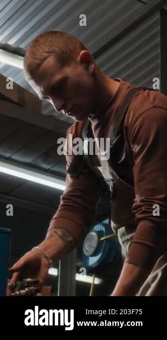 Vertical low angle shot of male Caucasian mechanic in uniform taking ...