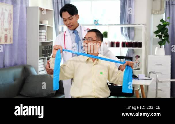 Physical therapist helps elderly Asian patient do physical therapy ...