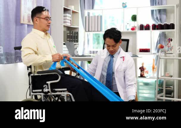 Physical therapist helps elderly Asian patient do physical therapy ...