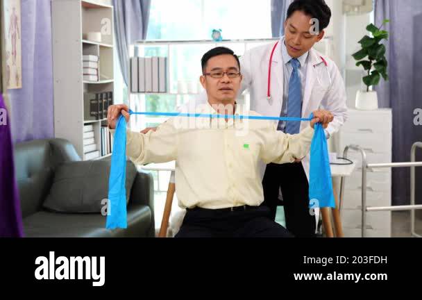 Physical therapist helps elderly Asian patient do physical therapy ...