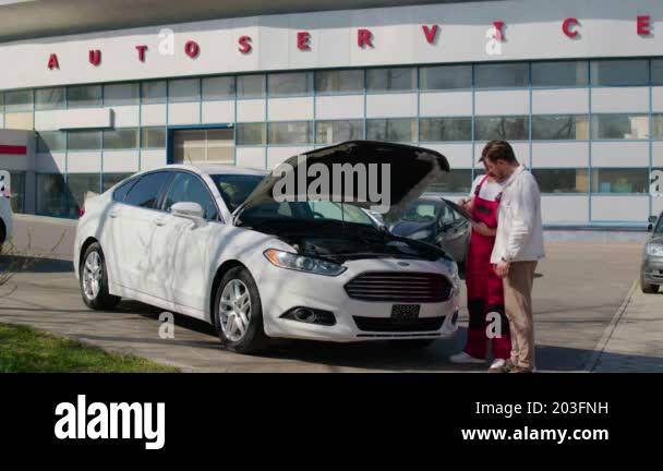Driver client talks to mechanic about results of car repair. Man in ...
