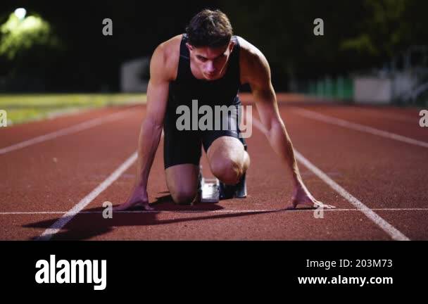 Strong Young Man Starting a Race From Track Starting Blocks Position on ...