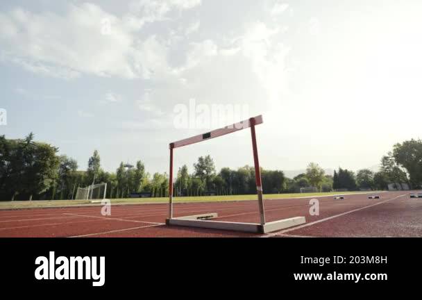 Businessman jumping a hurdle while running on the athletics racing ...