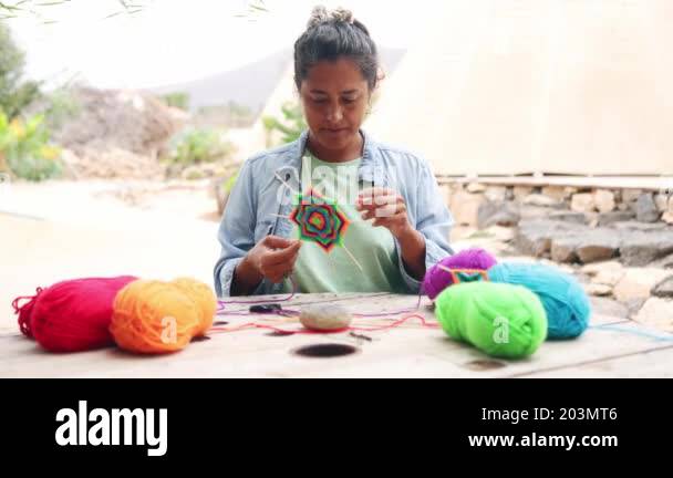 A woman deeply focused on her creative yarn craft outdoors, surrounded ...