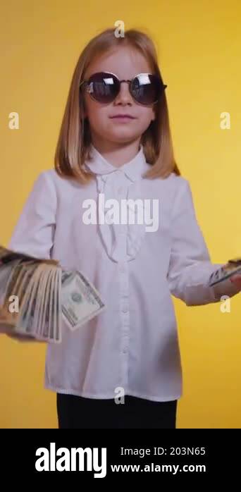 Vertical, a confident smiling child holds money dollars in her hands ...