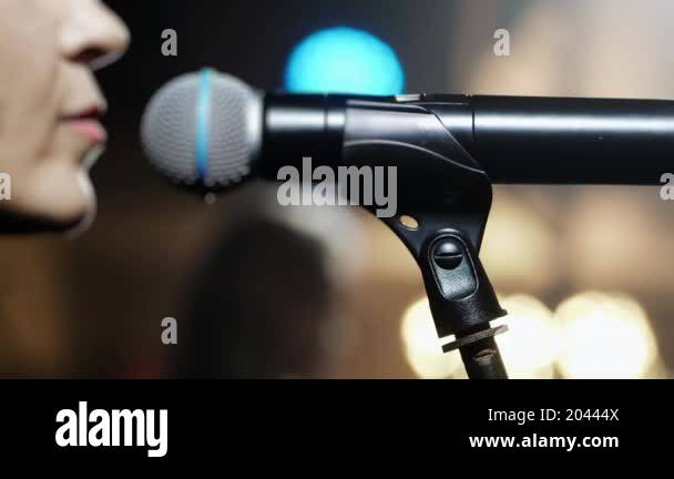 Close-up of a microphone on stage into which a young girl sings. The ...