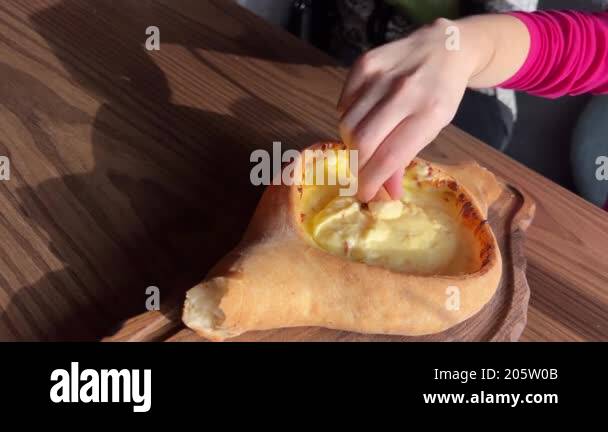 Womans hands tearing off a piece of Adjarian Khachapuri and dipping it ...