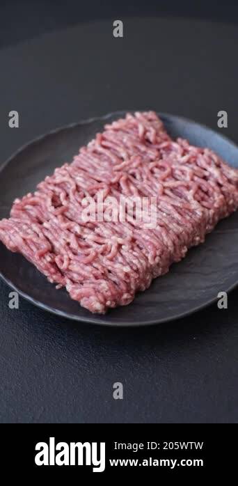 Fresh raw ground minced beef with salt and spices on textured concrete ...