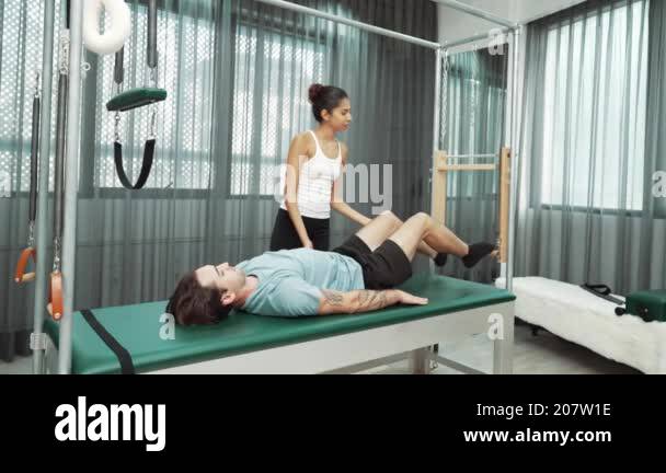 Skilled pilates instructor assisting a client in leg lift exercise on ...