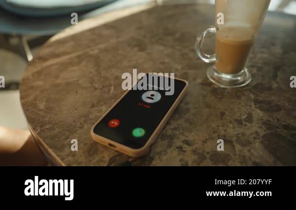 A close-up of a smartphone with a "SCAM" call notification highlights ...