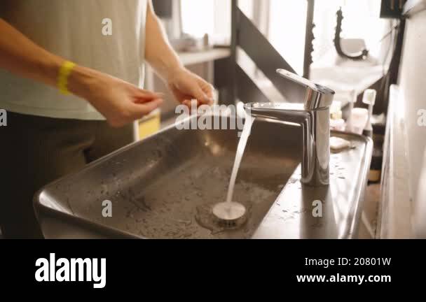 A close-up of a woman washing her hands under a sleek faucet, with ...