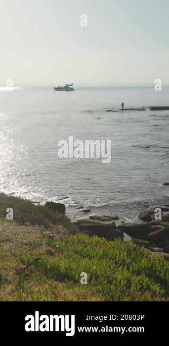 Vertical video. A rugged coastline with a small stone block in the ...