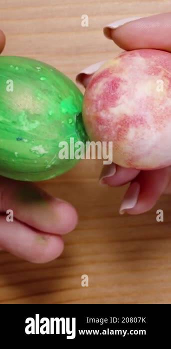 Vertical video. Men's and women's hands hold Easter eggs hitting each ...