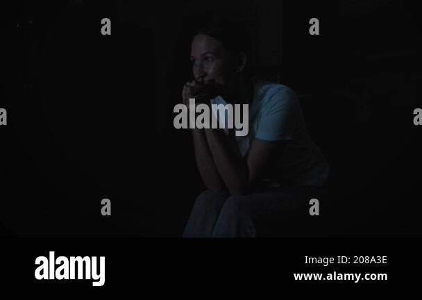 Young woman sitting on couch, expressing excitement and joy while ...
