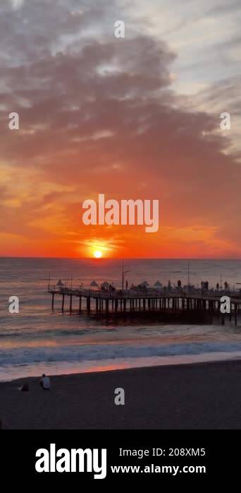 A breathtaking sunset view with a long pier, gentle waves, and vibrant ...