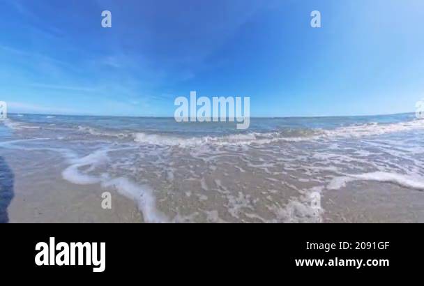Waves crashing onto a sandy beach from a low ground perspective ...