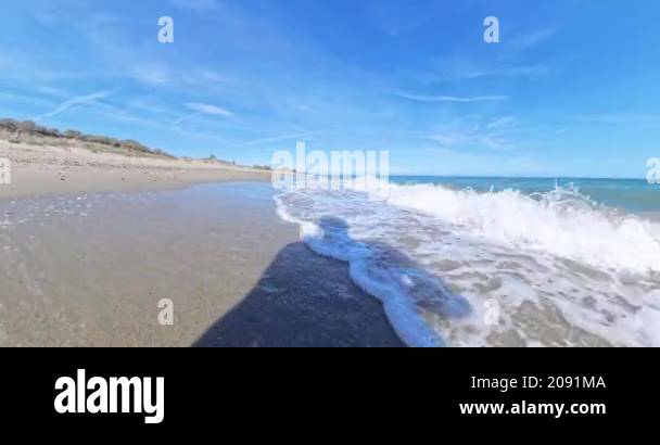 Waves crashing onto a sandy beach from a low ground perspective ...