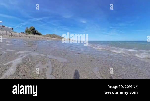 Waves crashing onto a sandy beach from a low ground perspective ...