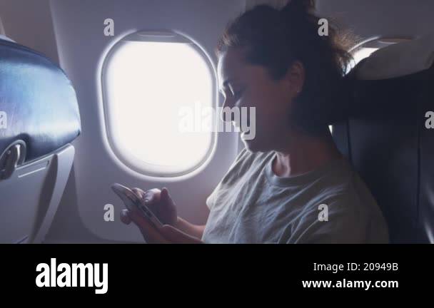 Passenger woman is flying in plane. Girl using phone sitting by ...