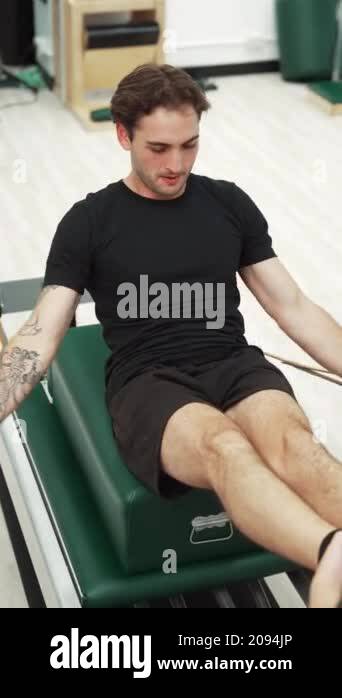 Man practicing seated arm pull exercise on pilates reformer to improve ...