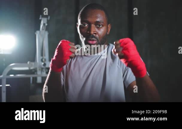Boxer in gym. Aggressive African man fighter resting after training ...