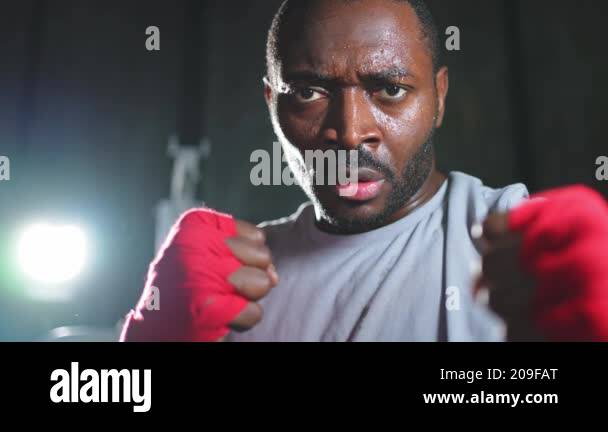 Boxer in gym. Aggressive African man fighter resting after training ...