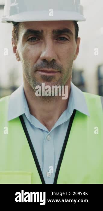 Portrait of man builder in reflective vest smiling while looking at ...