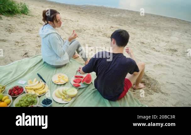 Mother and son eating raspberry at healthy food picnic near calm ...