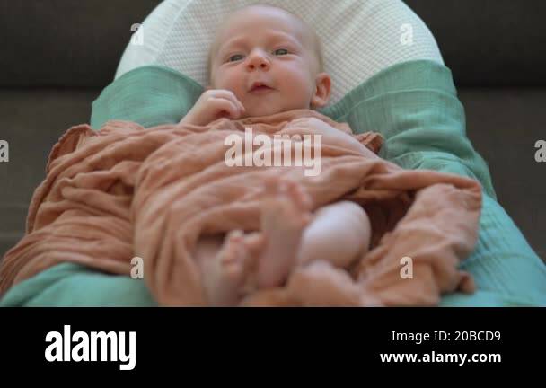 A newborn baby rests peacefully in a comfortable baby cocoon, covered ...
