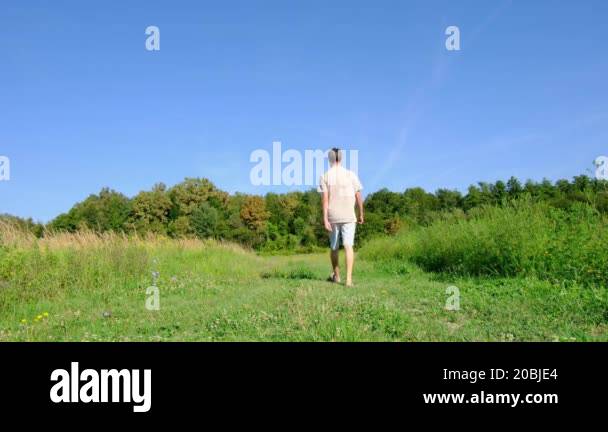 Man walking along a narrow path, surrounded by natural landscape ...